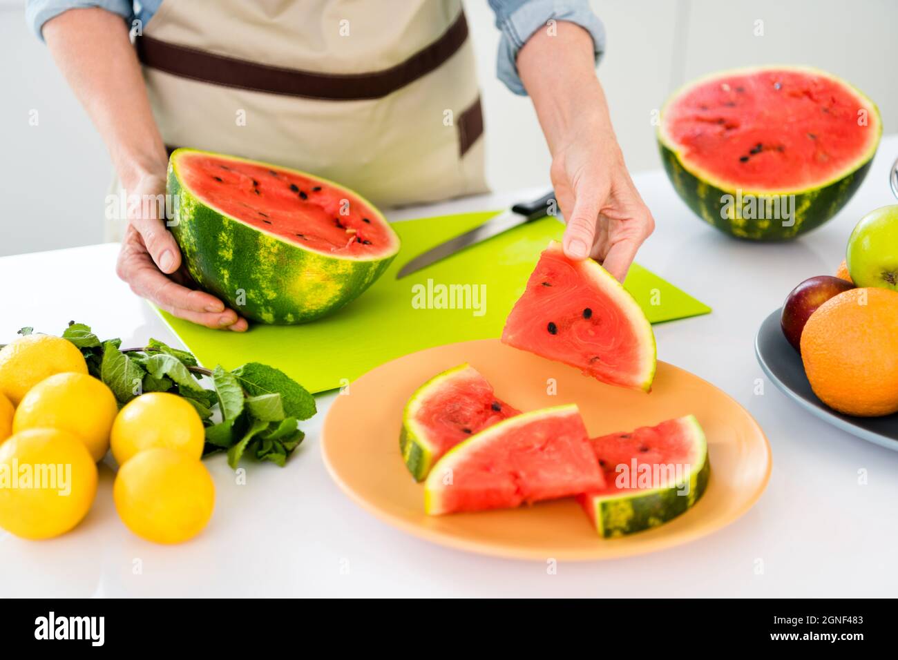 Cropped photo of mature lady cut watemalon wear apron at kitchen alone ...