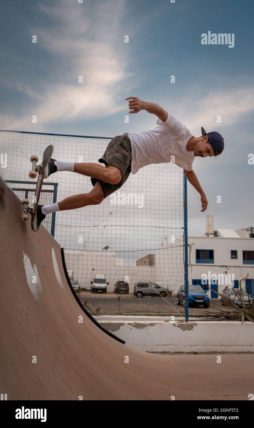young man skateboarding on the ramp of a skate park. vertical ...