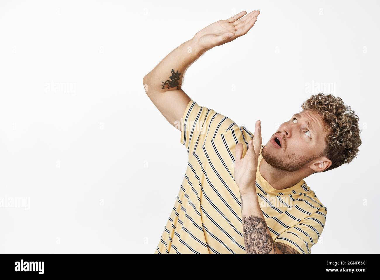 Scared guy defending himself from something falling from above, bending ...