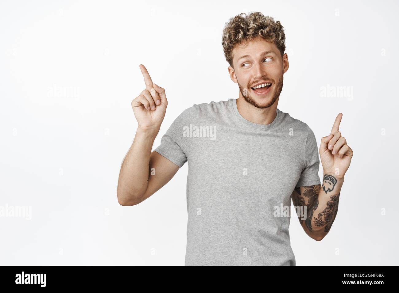 Joyful blond guy dancing while making choice, smiling and pointing ...