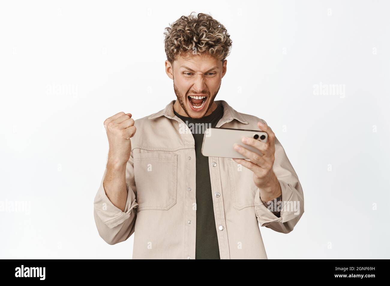 Happy blond man looking at smartphone and shouting with joy, happy guy ...