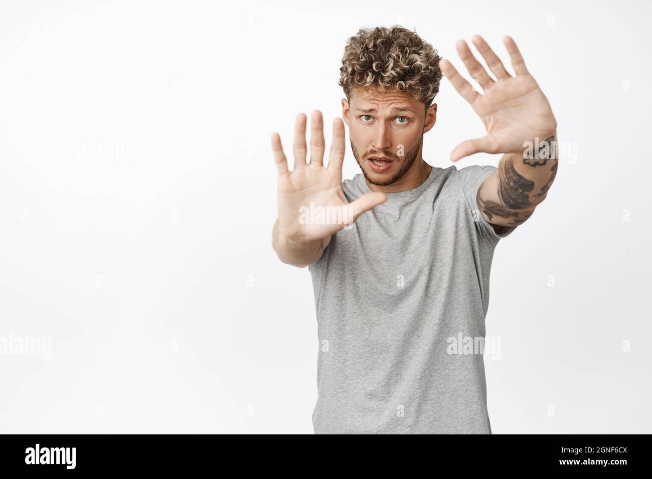 Creative stylish young man with tattoos, looking through hands frame ...