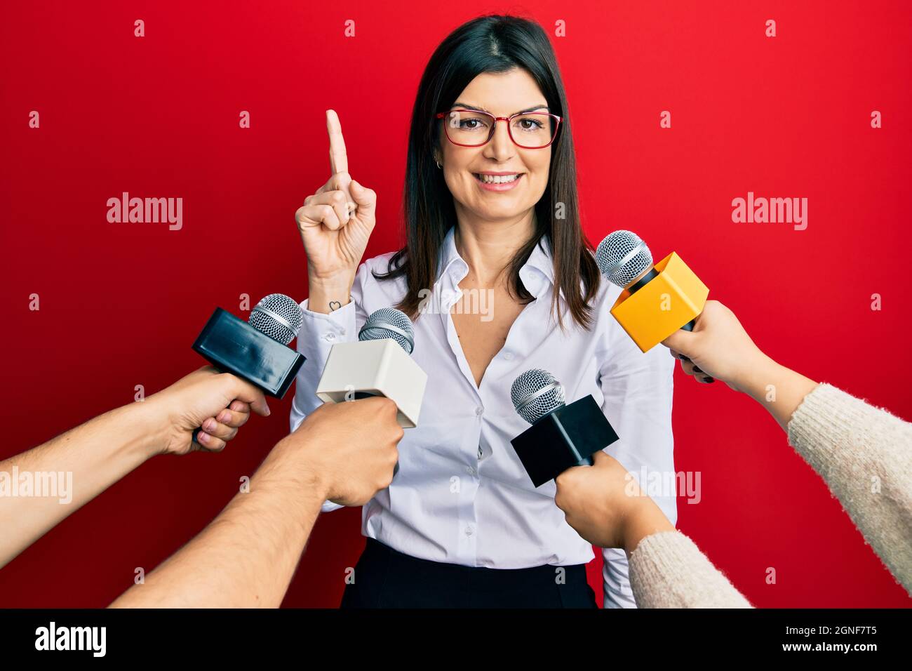 Young hispanic woman being interviewed for journalist hands with ...