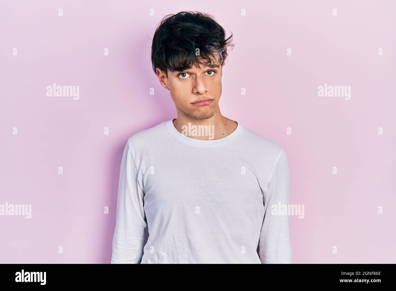Handsome hipster young man wearing casual white shirt depressed and ...
