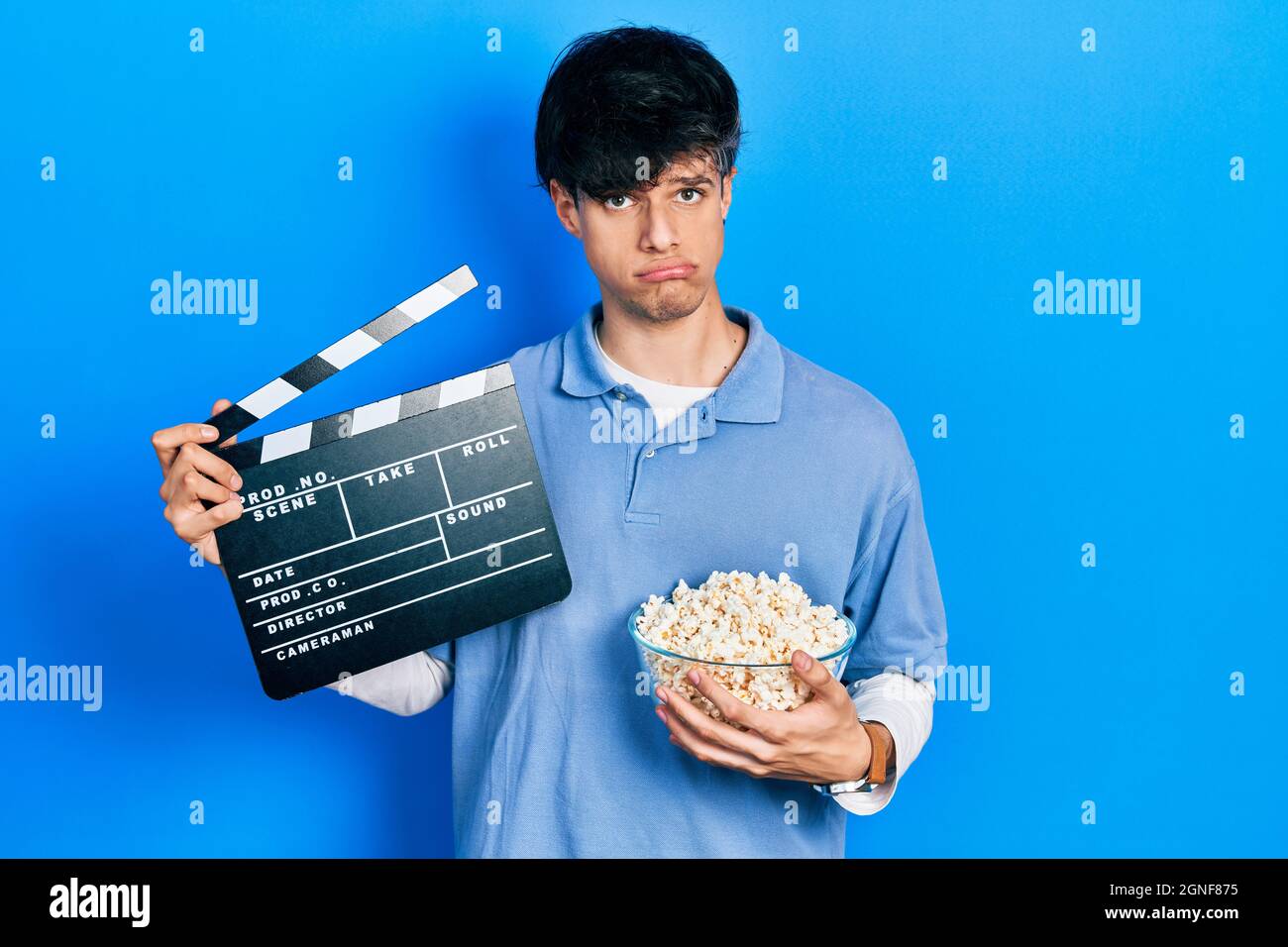 Handsome hipster young man eating popcorn holding cinema clapboard ...