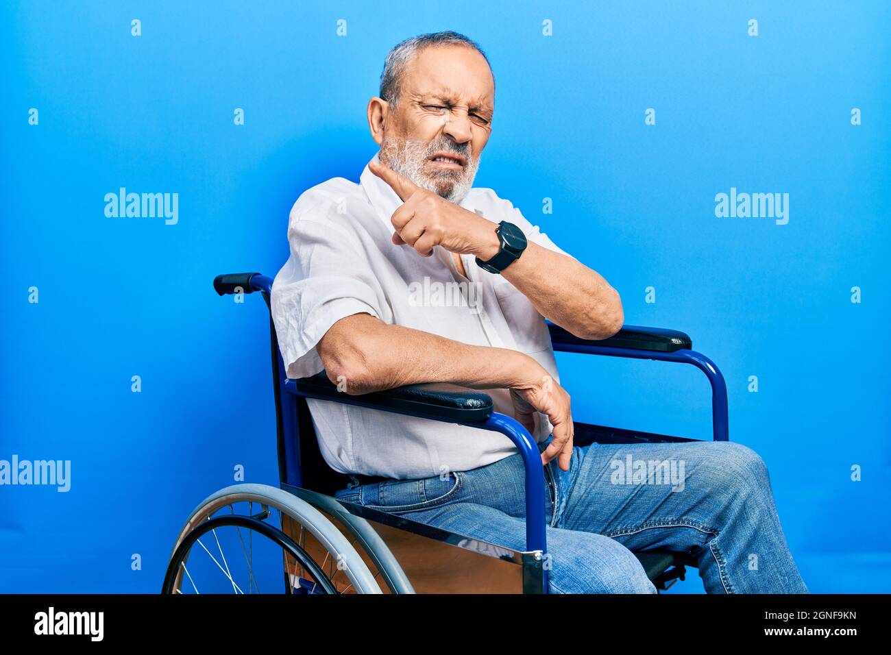 Handsome senior man with beard sitting on wheelchair pointing aside ...