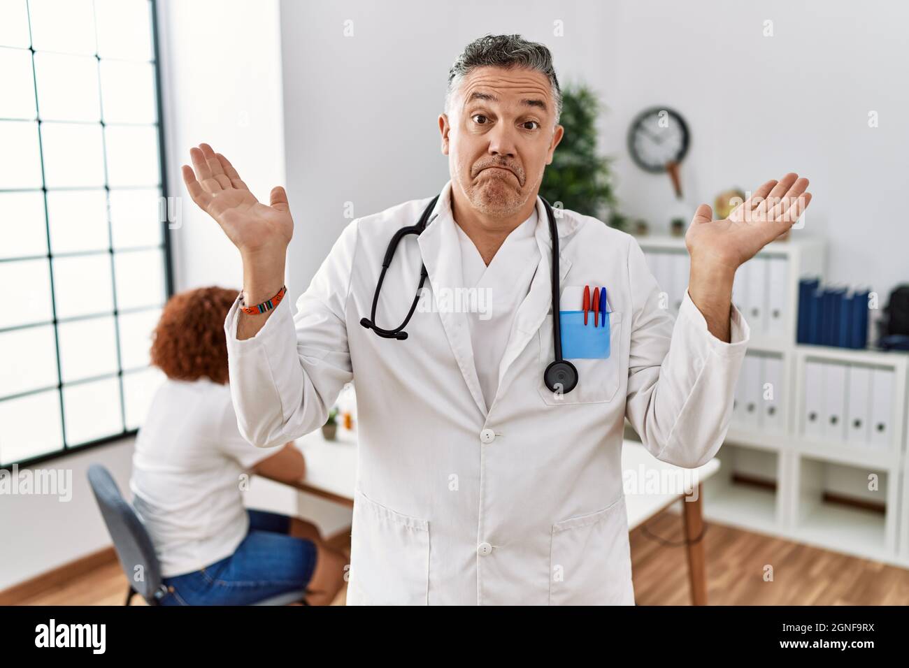 Middle age doctor man at the clinic with a patient clueless and ...
