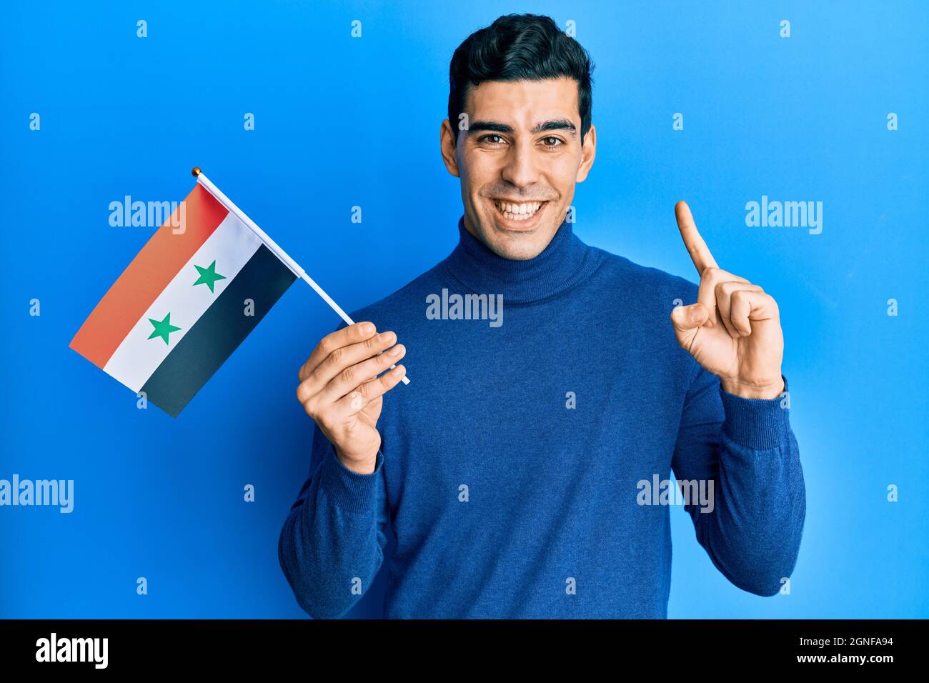Handsome hispanic man holding syria flag smiling with an idea or ...