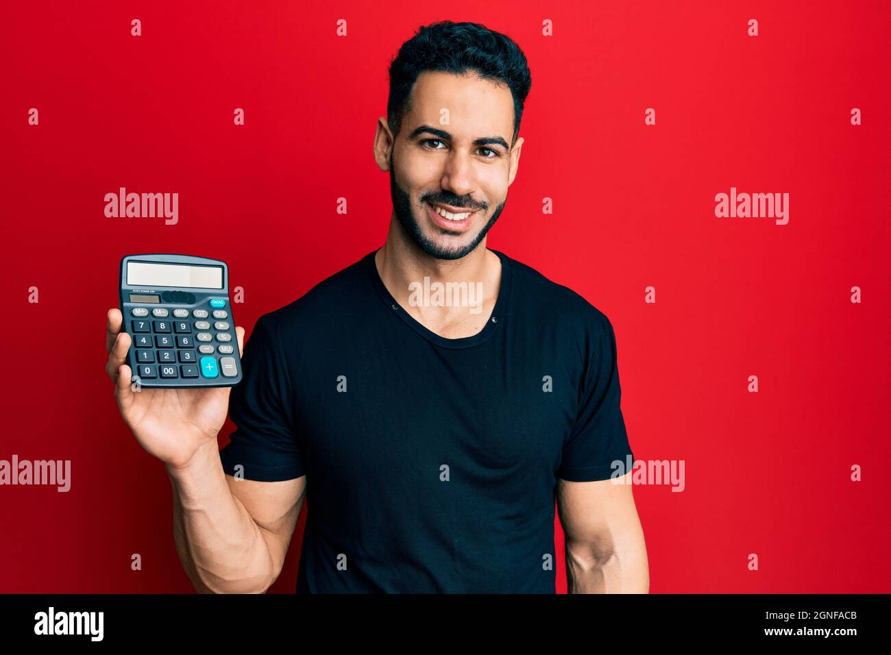 Young hispanic man showing calculator device looking positive and happy ...
