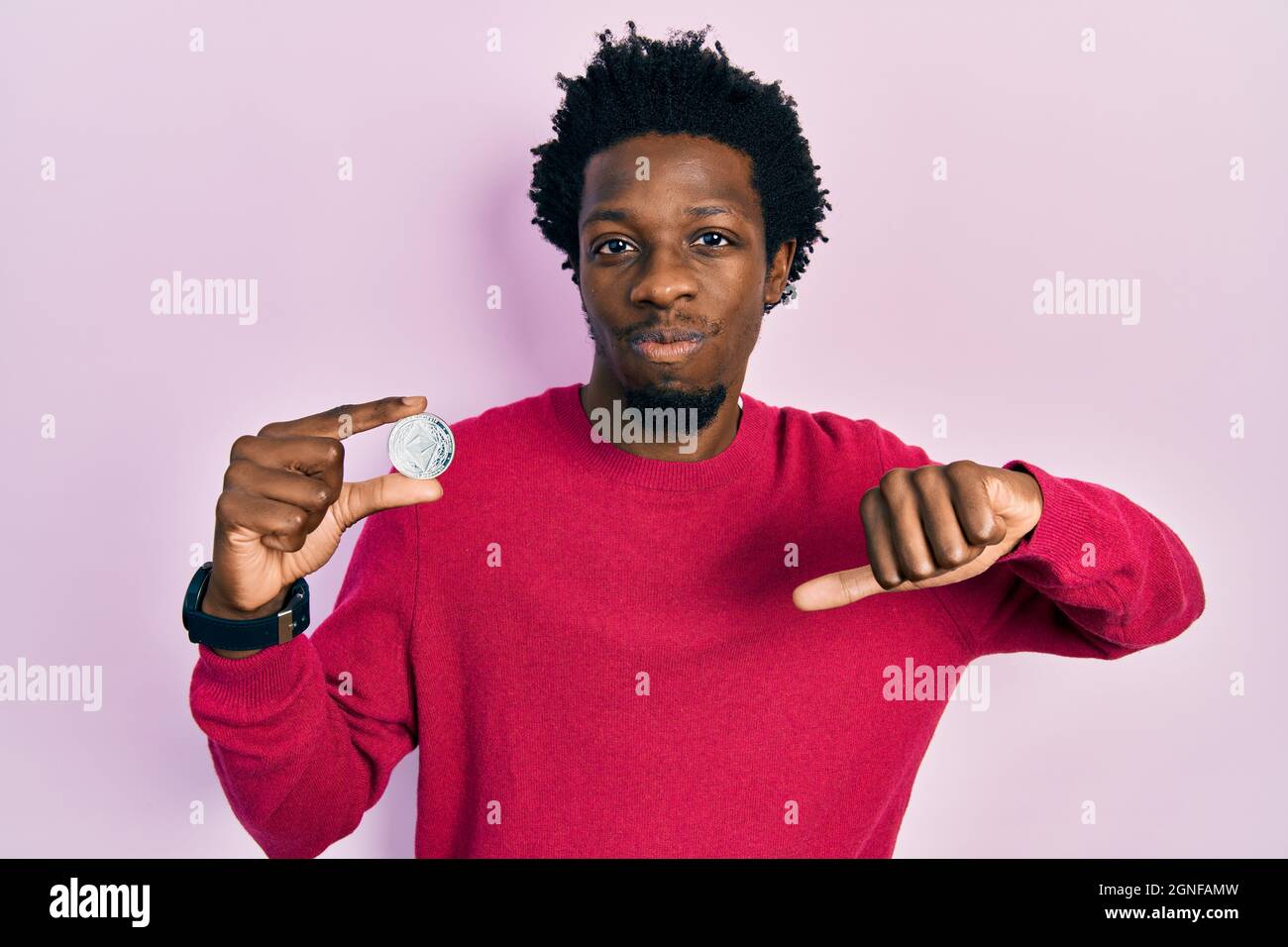 Young african american man holding virtual currency ethereum coin with ...