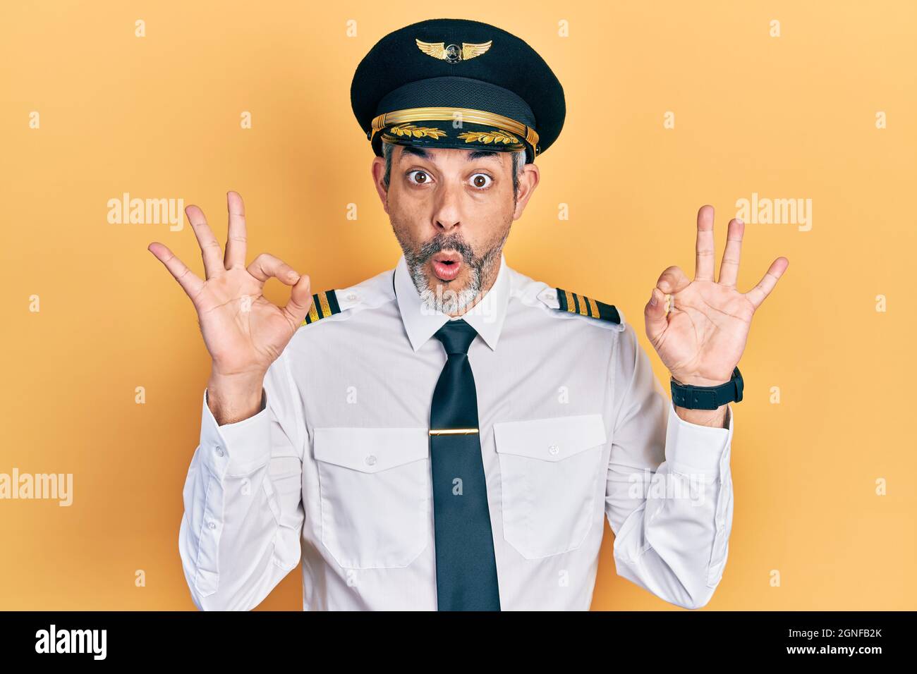 Handsome middle age man with grey hair wearing airplane pilot uniform ...