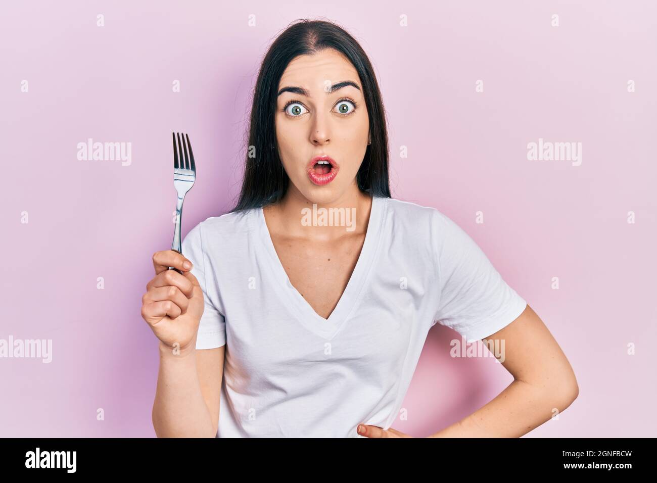 Beautiful woman with blue eyes holding one silver fork scared and ...