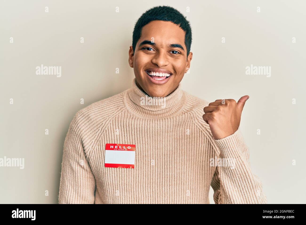 Young handsome hispanic man wearing hello my name is sticker ...