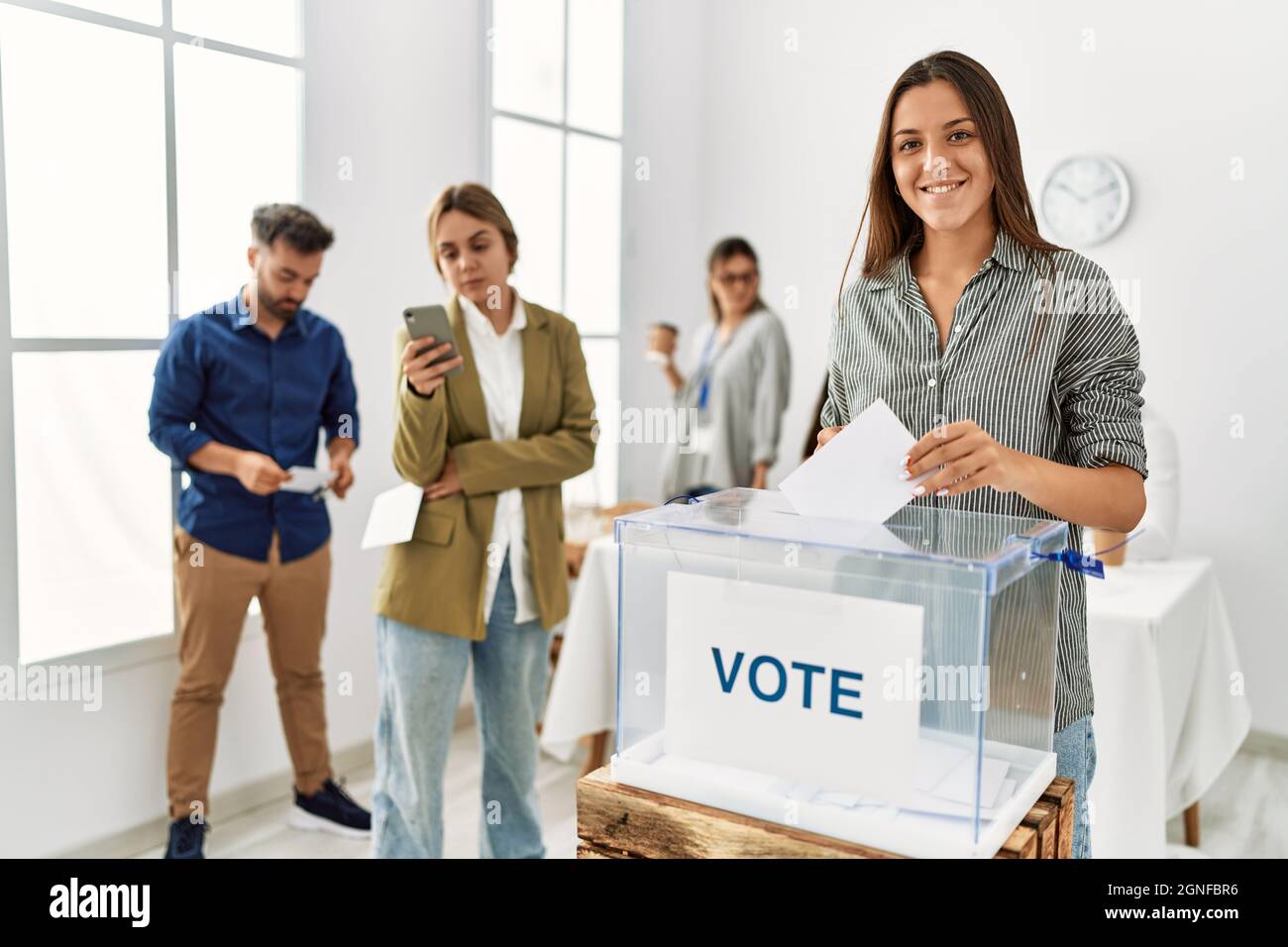 Young voter woman smiling happy putting vote in voting box at electoral ...