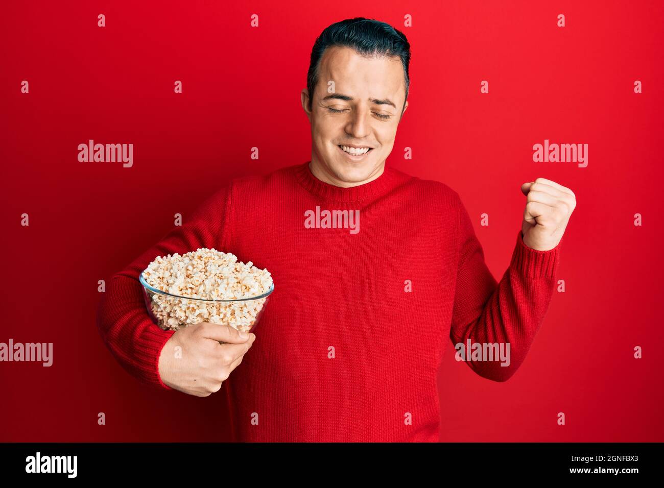Handsome young man eating popcorn screaming proud, celebrating victory ...