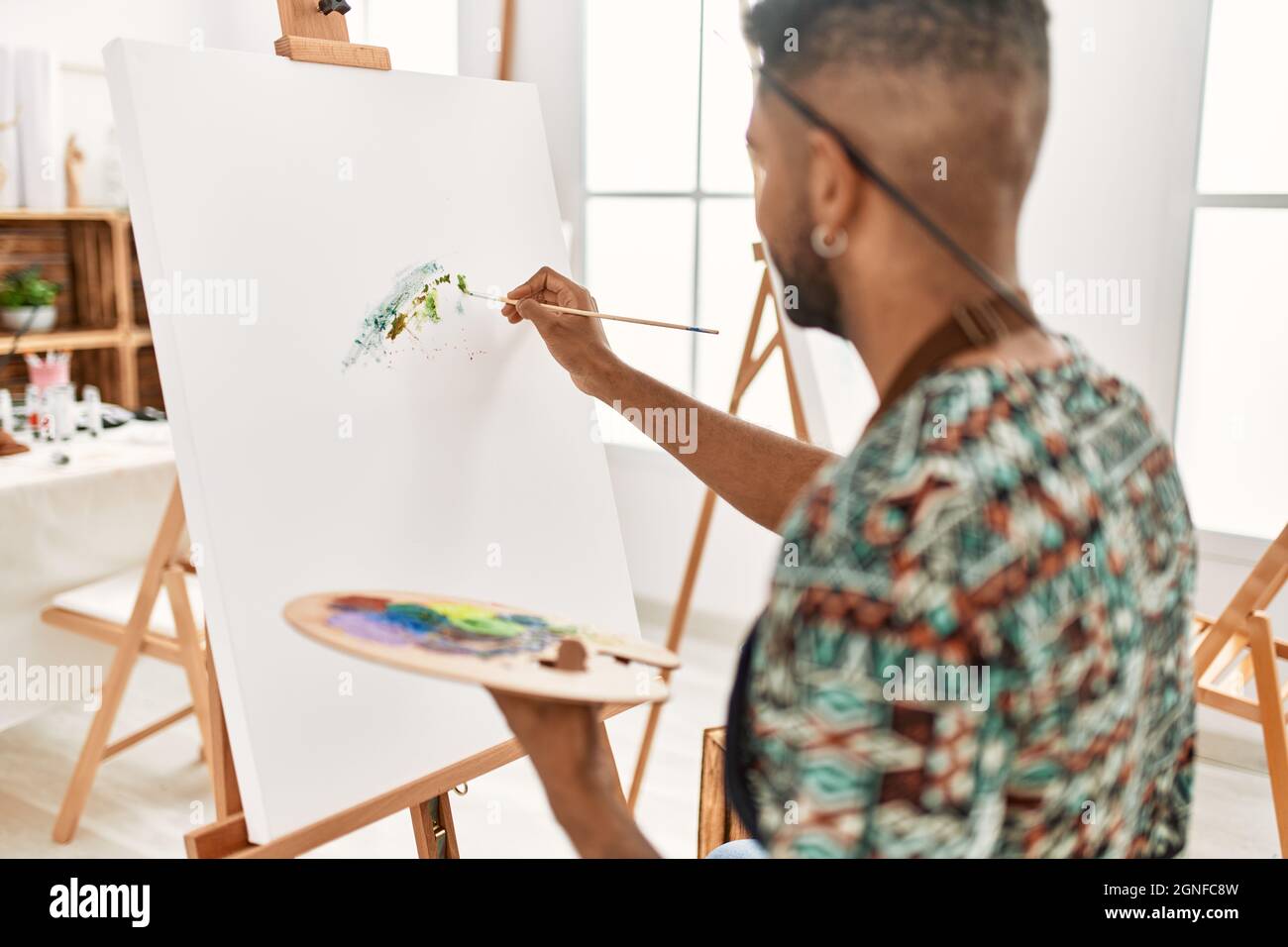 Young african american artist man on back view painting at art studio ...
