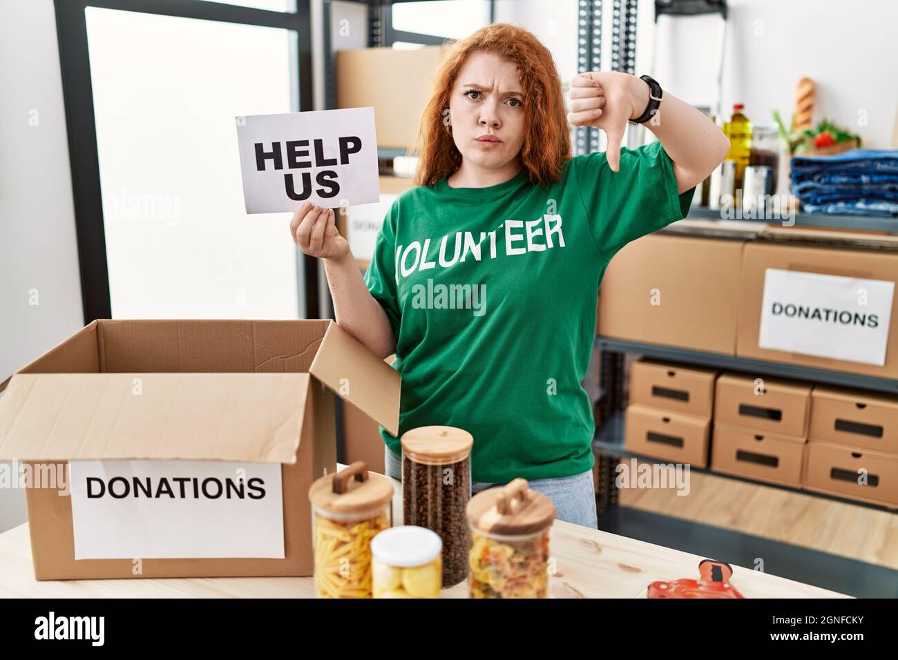 Young redhead woman wearing volunteer t shirt holding help us banner ...
