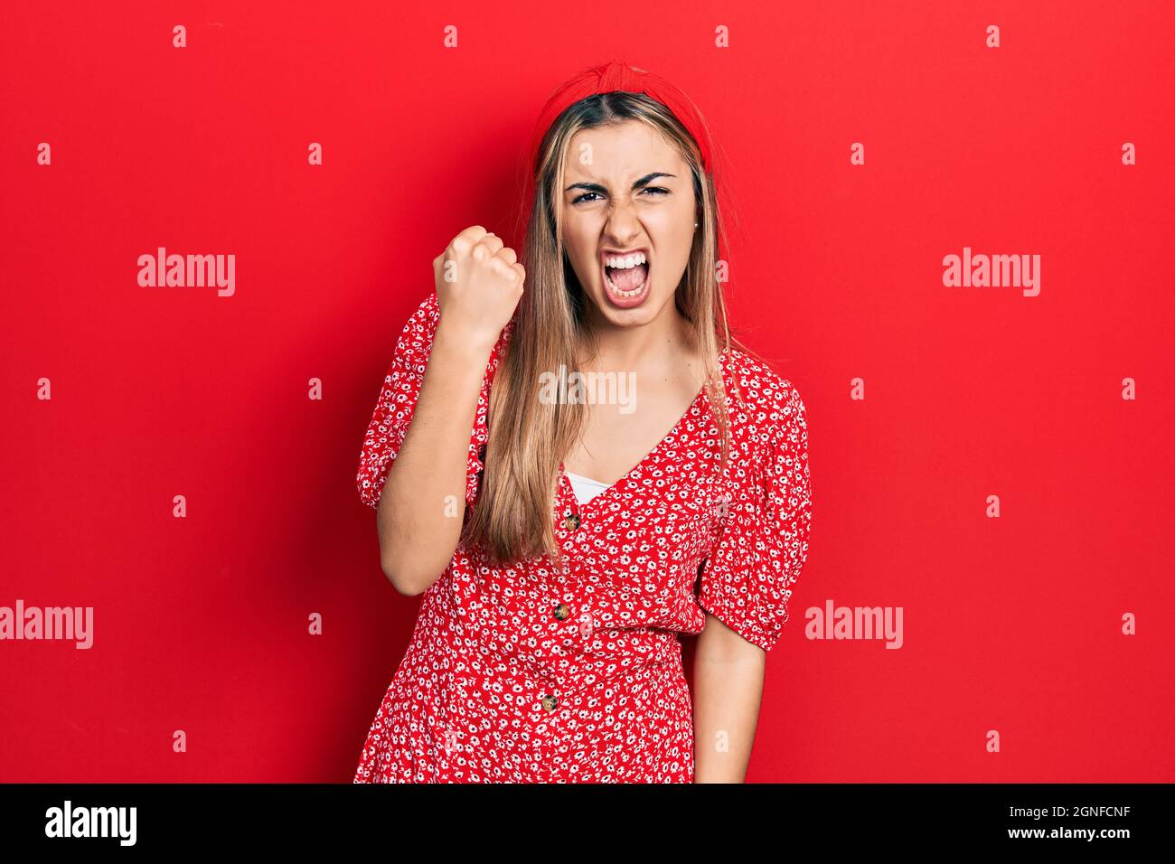 Beautiful hispanic woman wearing summer dress angry and mad raising ...