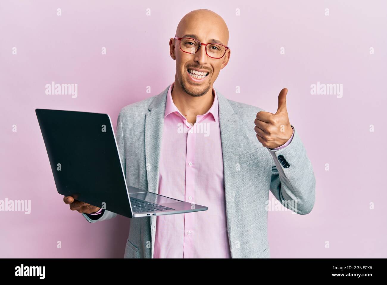 Bald man with beard holding laptop smiling happy and positive, thumb up ...