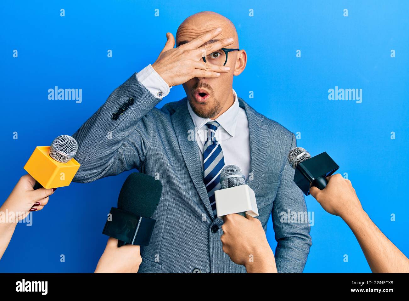Bald man with beard being interviewed by reporters holding microphones ...