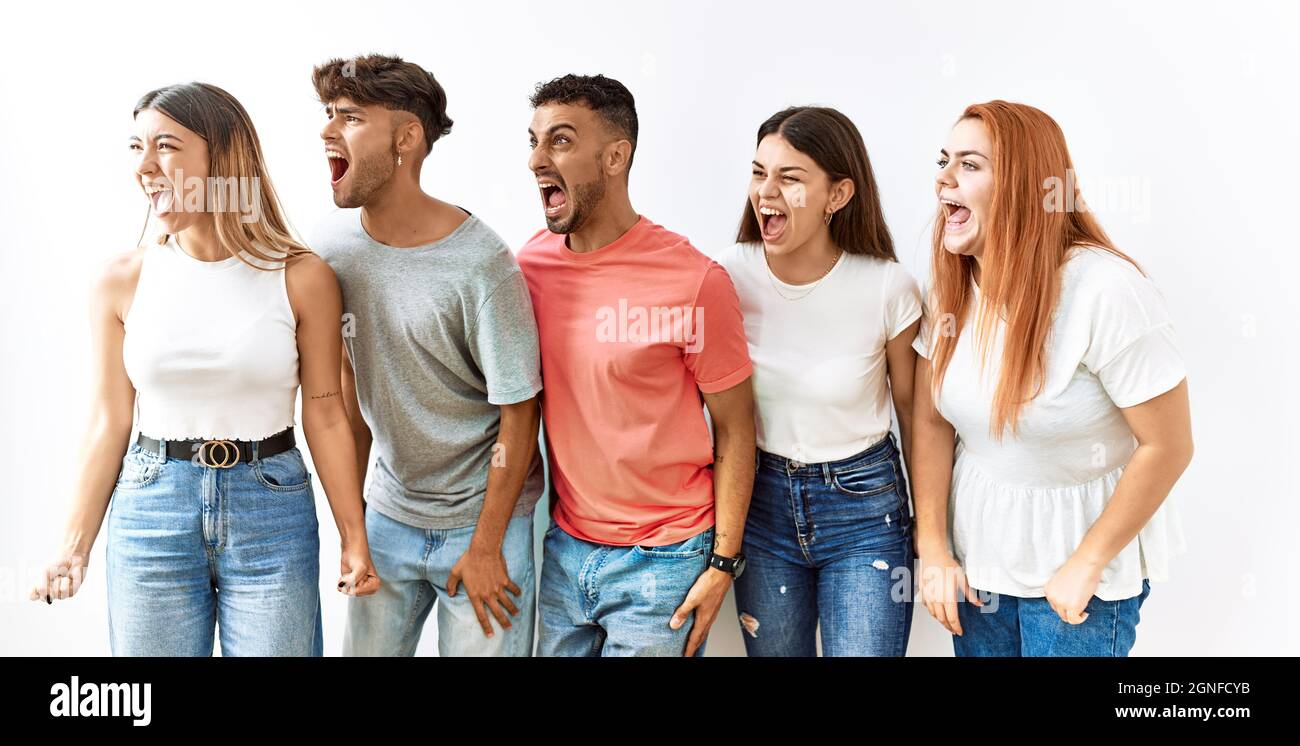 Group of young friends standing together over isolated background angry ...