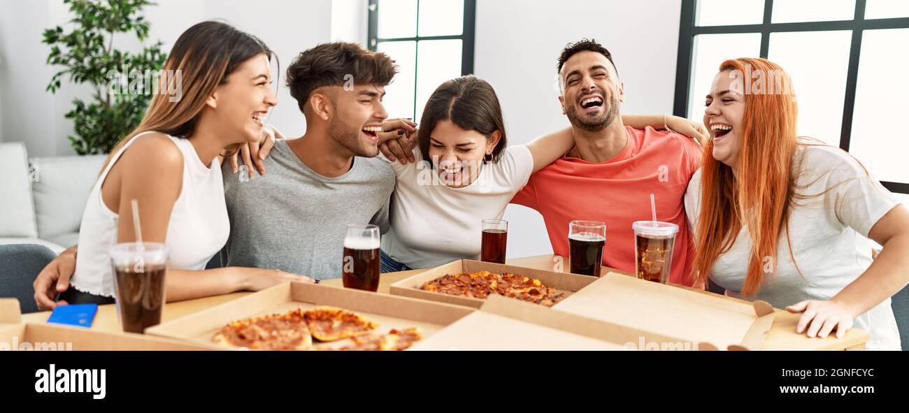Group of young people smiling happy and hugging eating italian pizza at ...