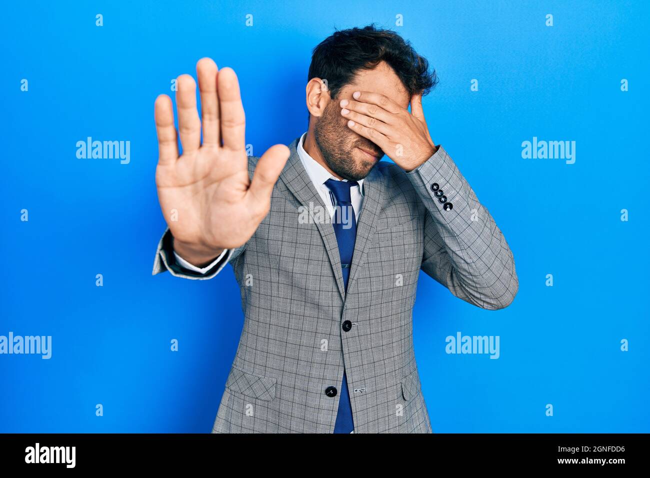 Handsome man with beard wearing business suit and tie covering eyes ...