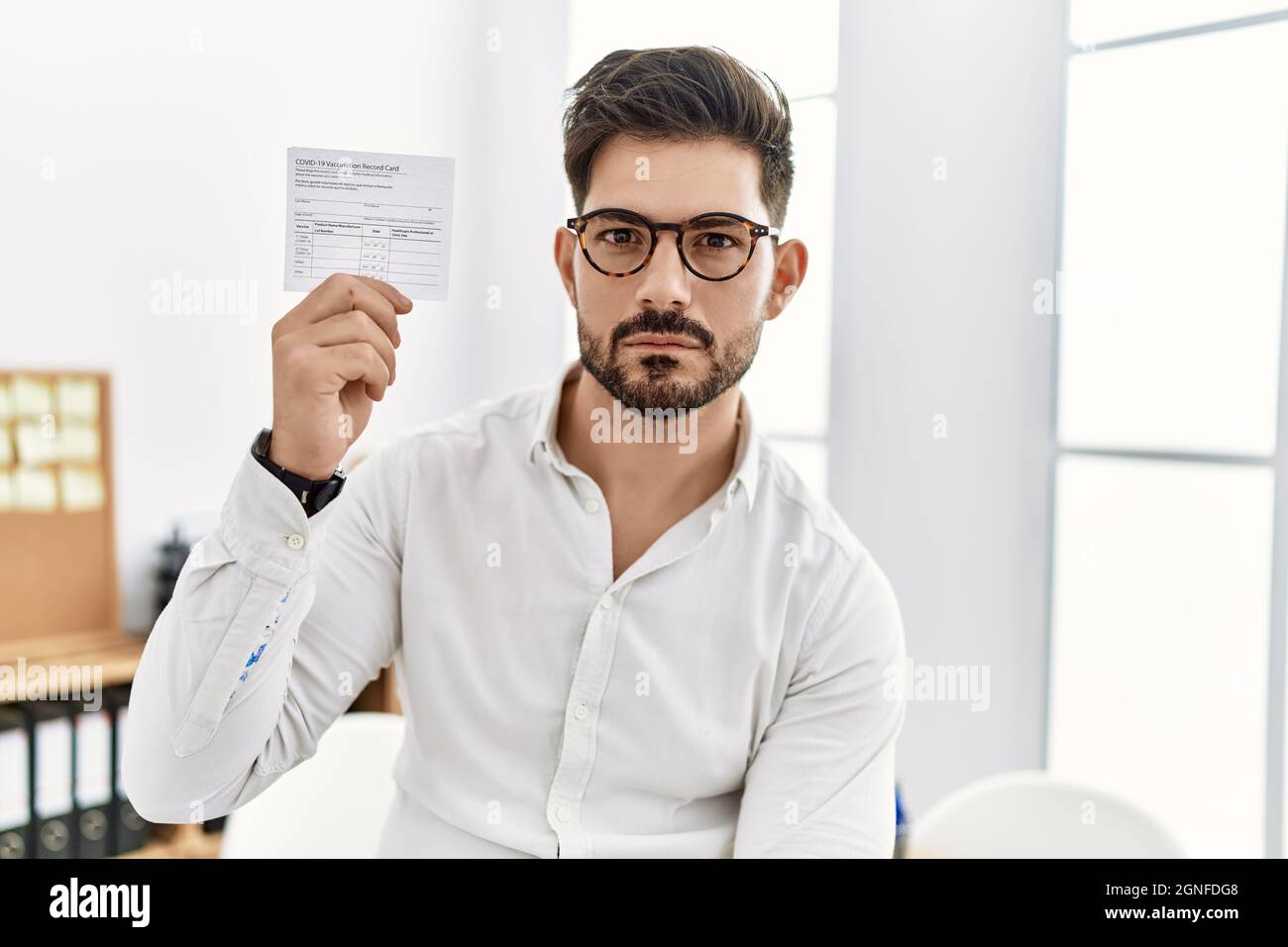Young man with beard holding covid record card thinking attitude and ...