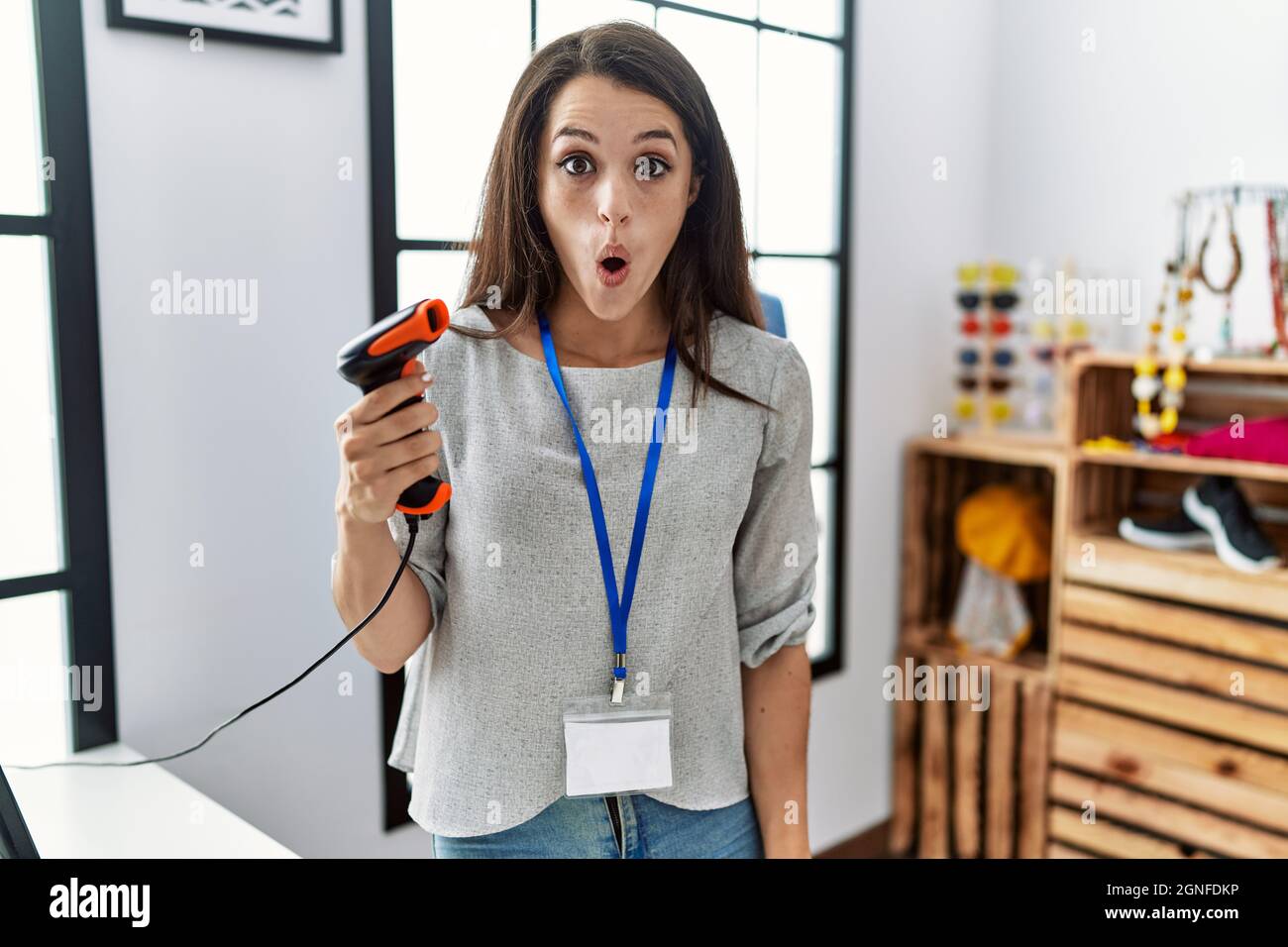 Young brunette woman working at retail store holding barcode reader ...