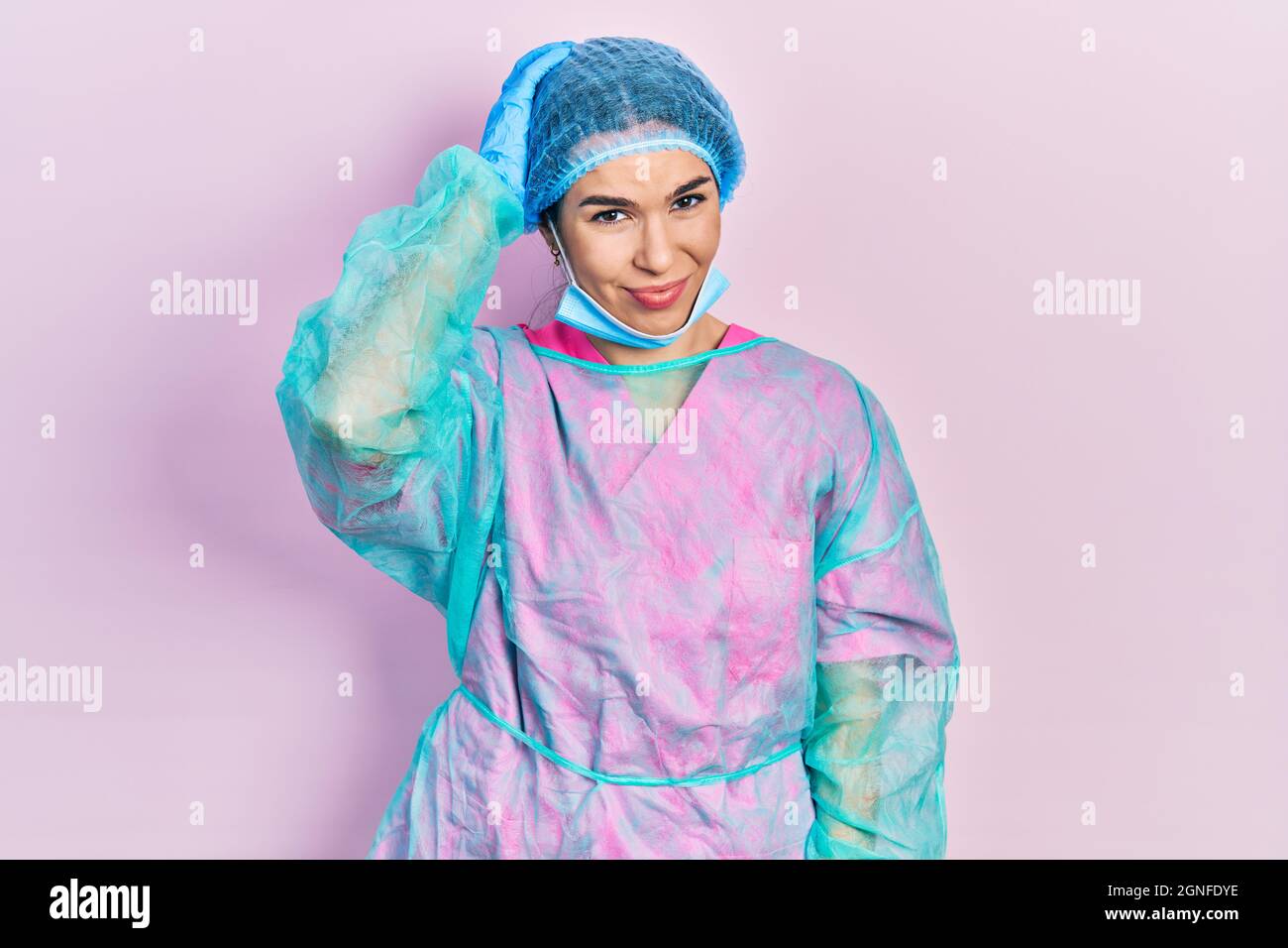 Young brunette woman wearing surgeon uniform and medical mask confuse ...