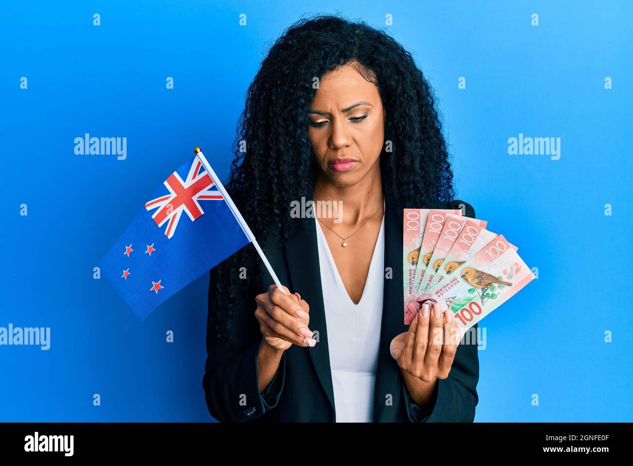Middle age african american woman holding new zealand flag and dollars ...