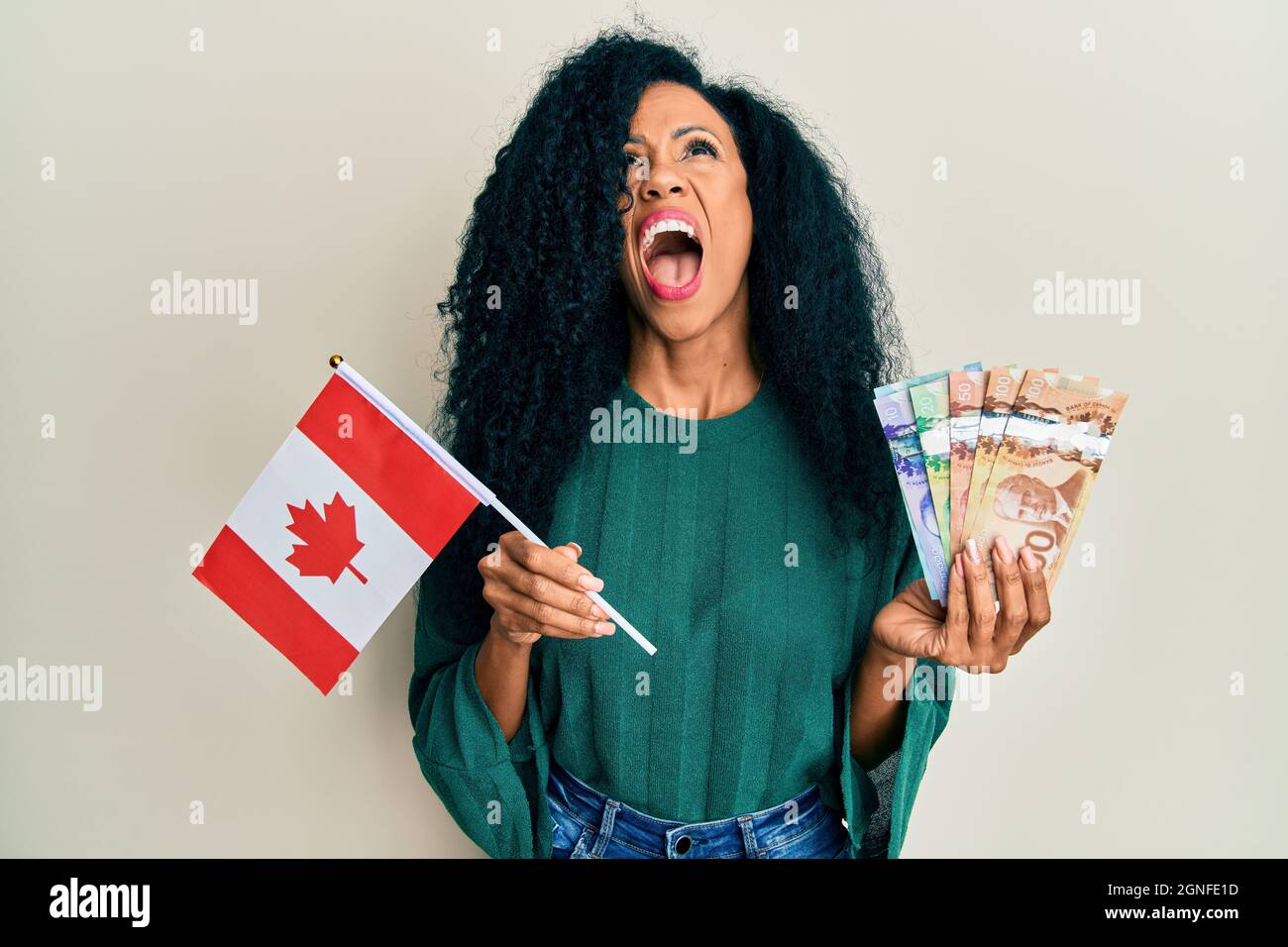 Middle age african american woman holding canada flag and dollars angry ...