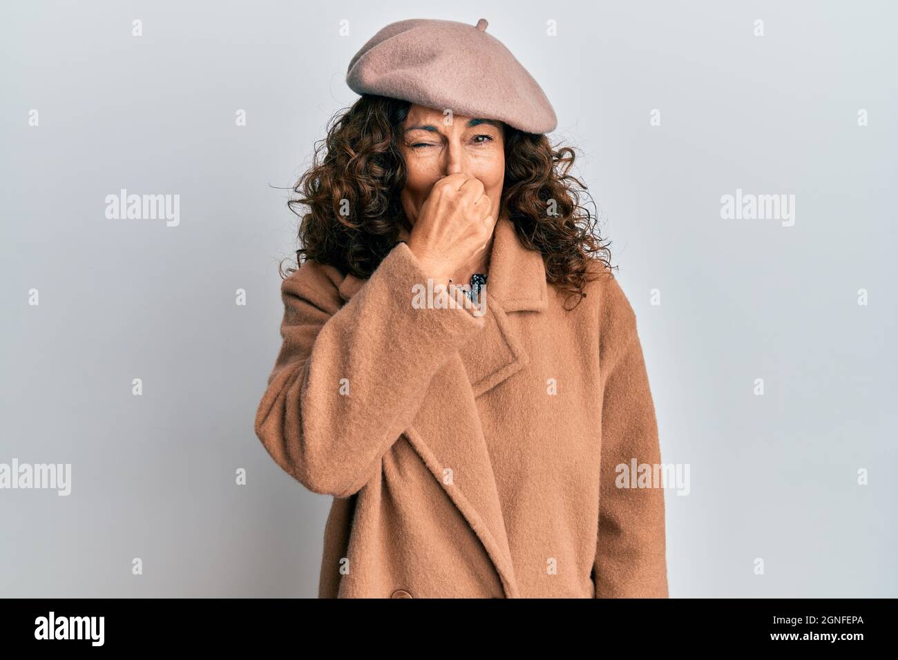 Middle age hispanic woman wearing french look with beret smelling ...