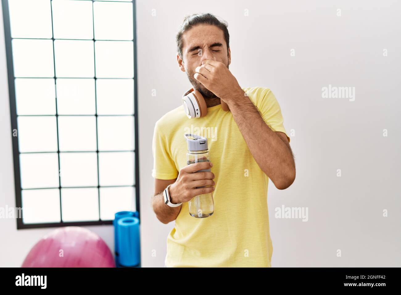 Young hispanic man wearing sportswear and drinking water at the gym ...