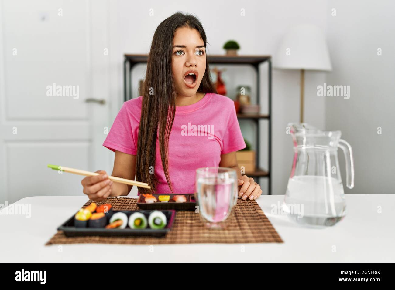 Young brunette woman eating sushi using chopsticks angry and mad ...
