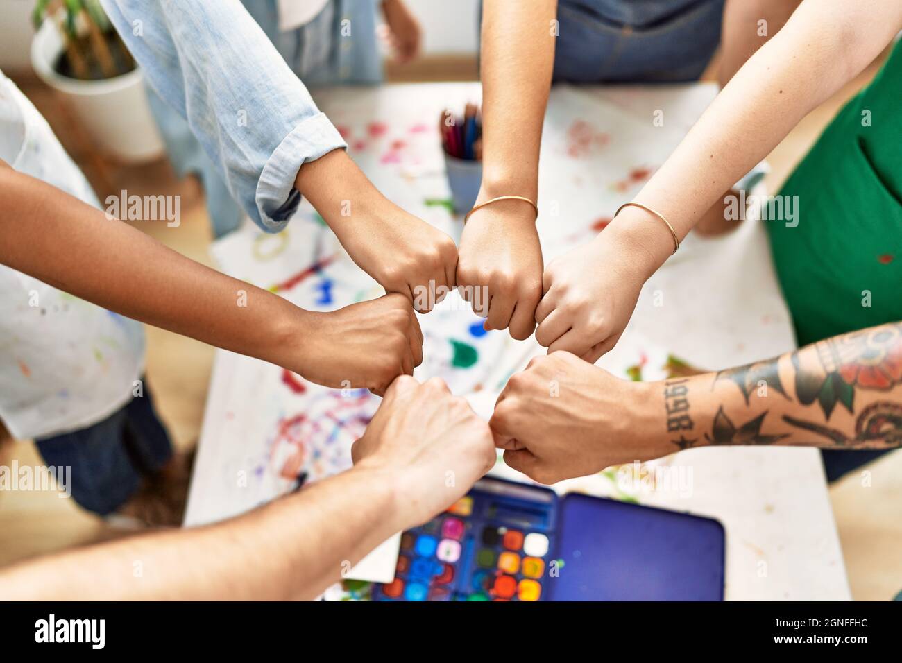 Group of people sitting on the table bump fists at art studio Stock ...