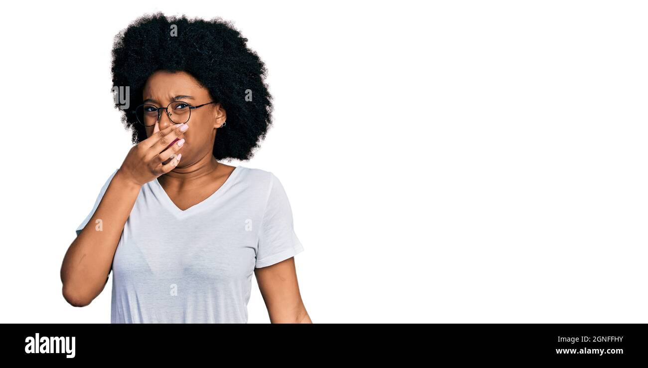 Young african american woman wearing casual white t shirt smelling ...