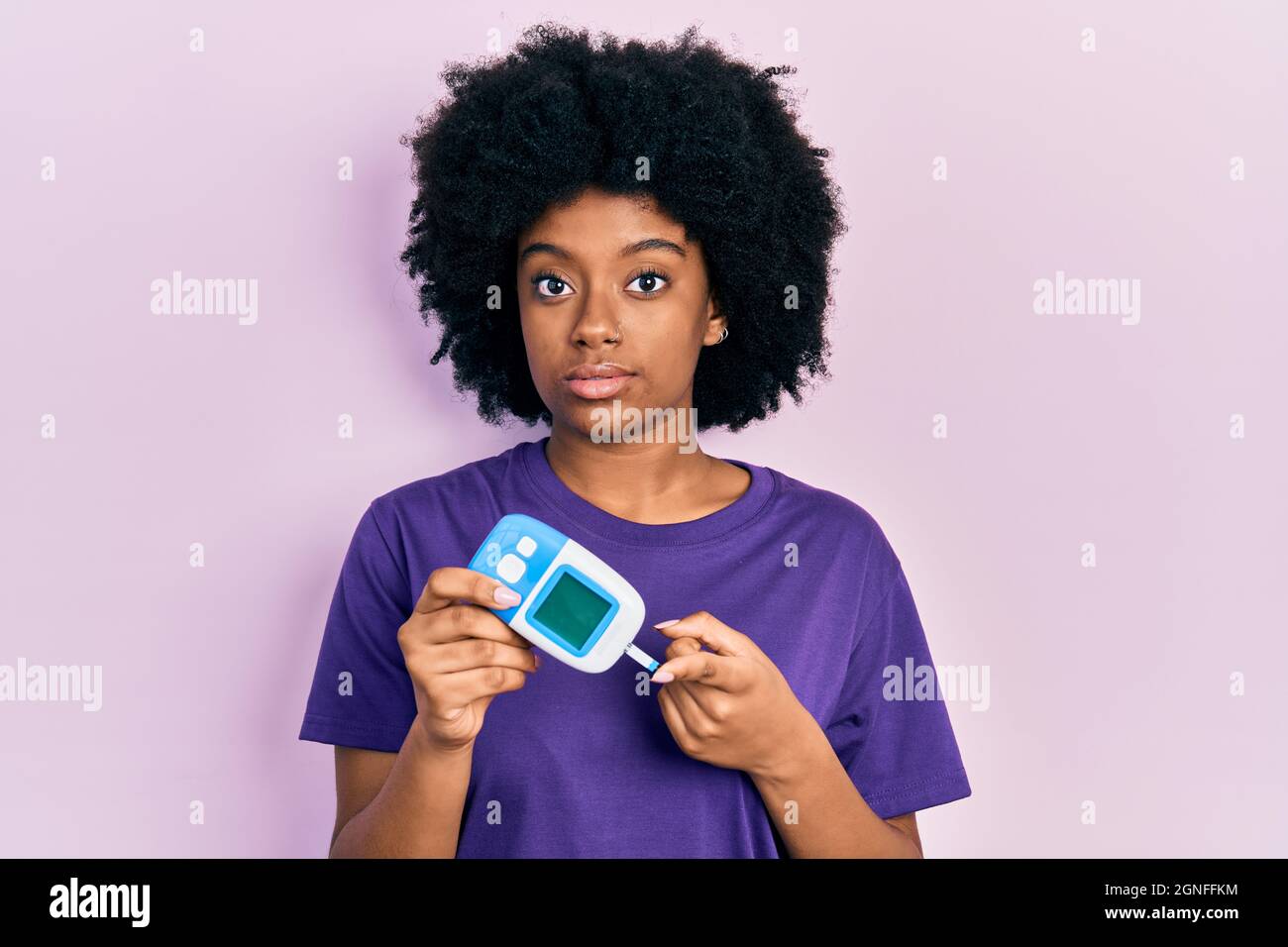 Young african american woman holding glucometer device relaxed with ...