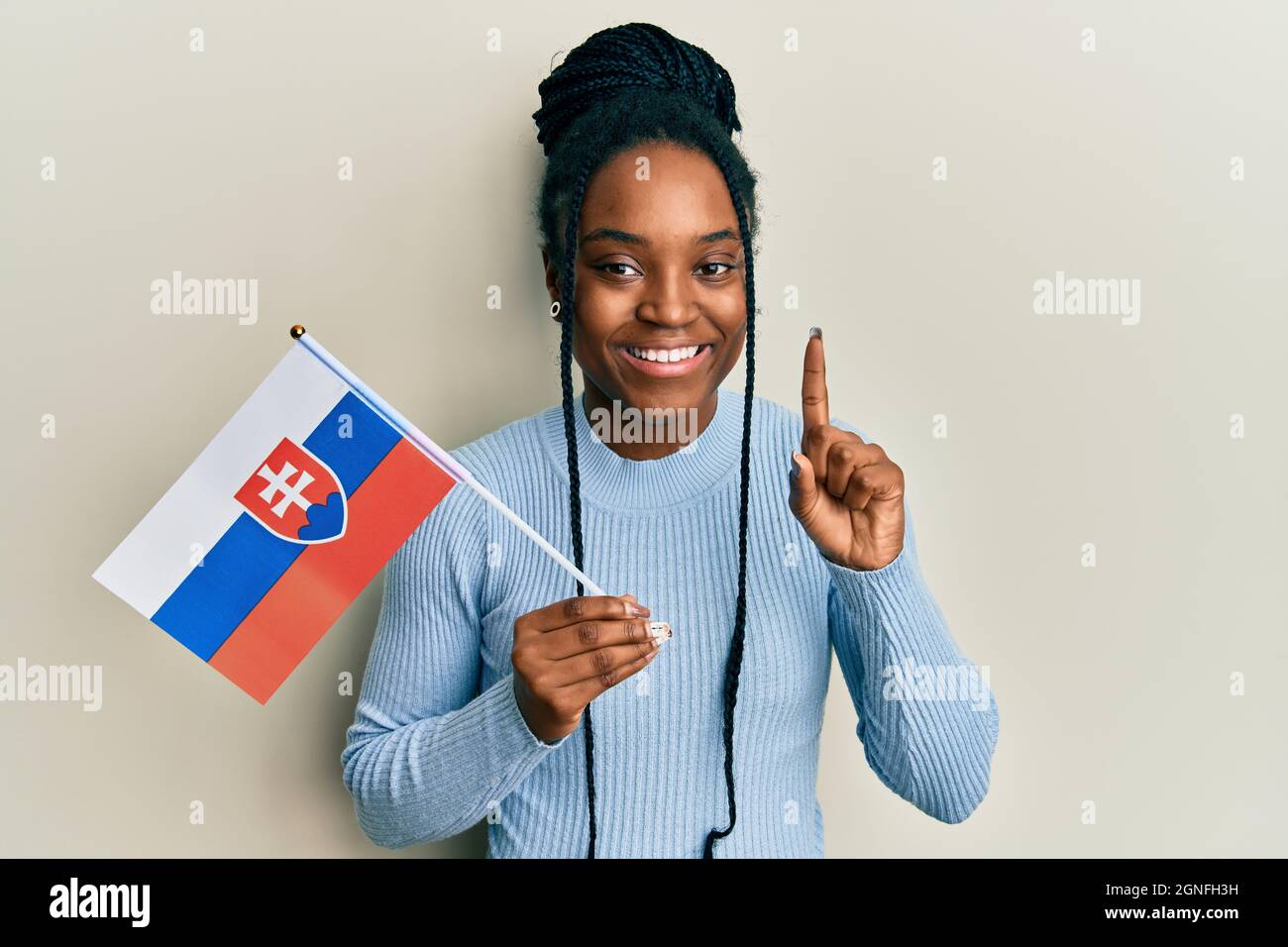 African american woman with braided hair holding slovakia flag smiling ...