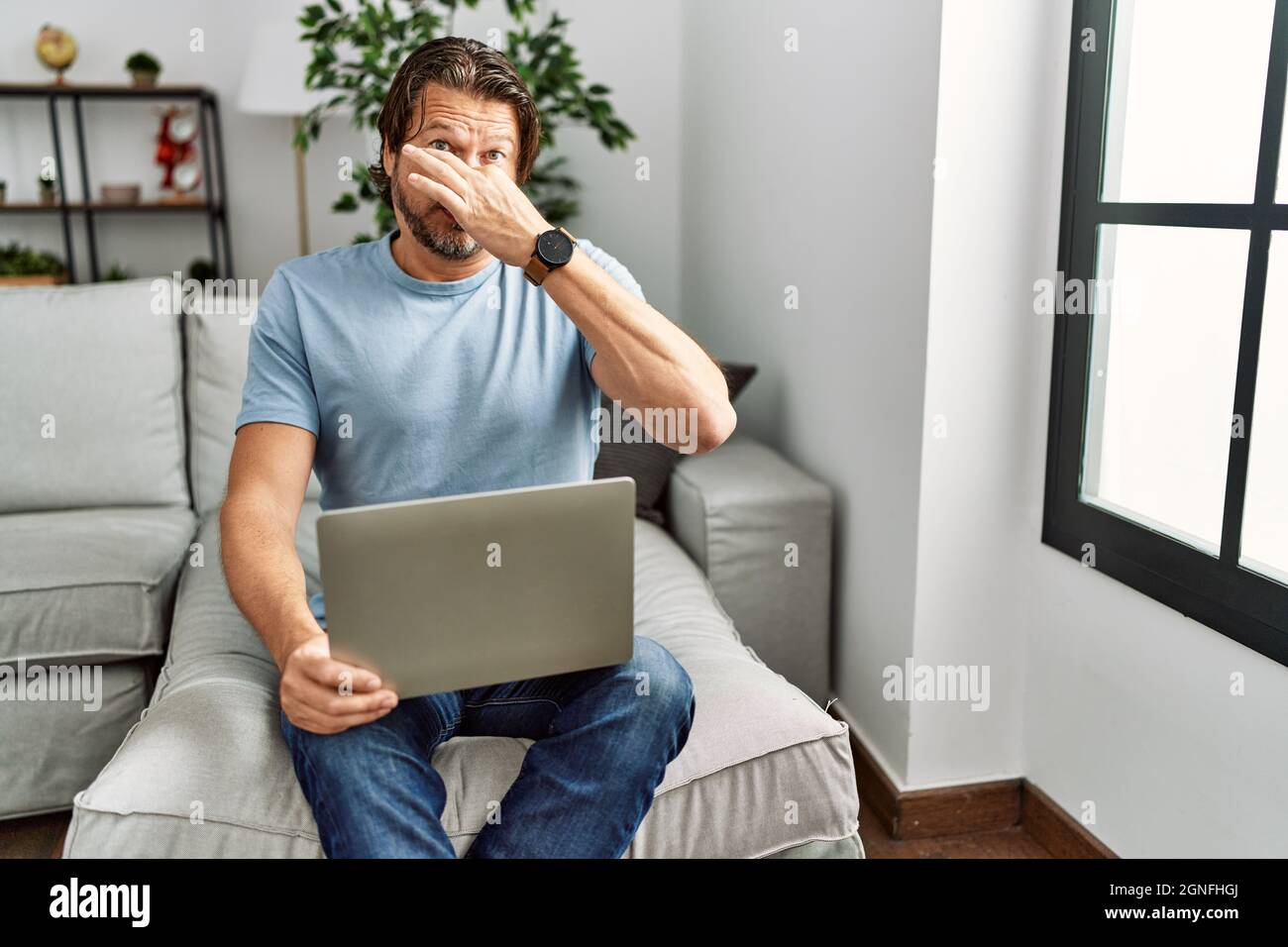 Handsome middle age man using computer laptop on the sofa smelling ...