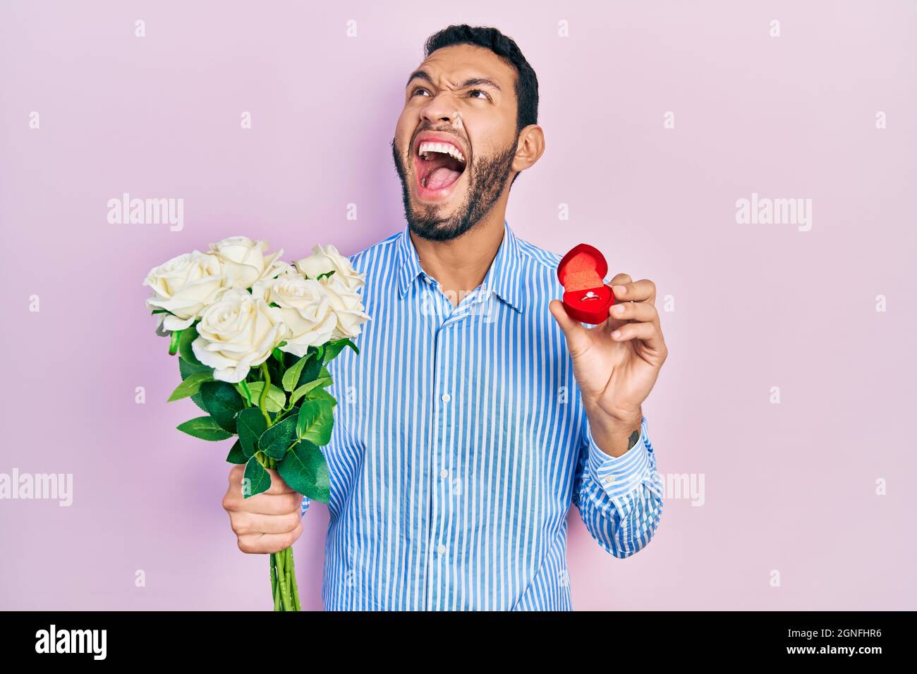 Hispanic man with beard holding bouquet of flowers and engagement ring ...