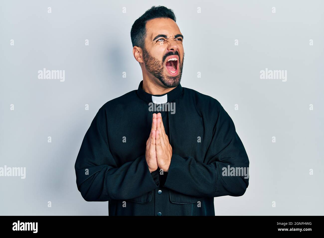 Handsome hispanic priest man with beard standing over isolated ...