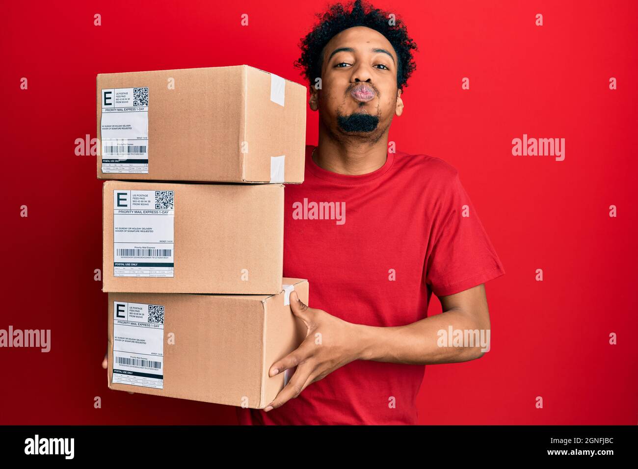 Young african american man with beard holding delivery packages puffing ...
