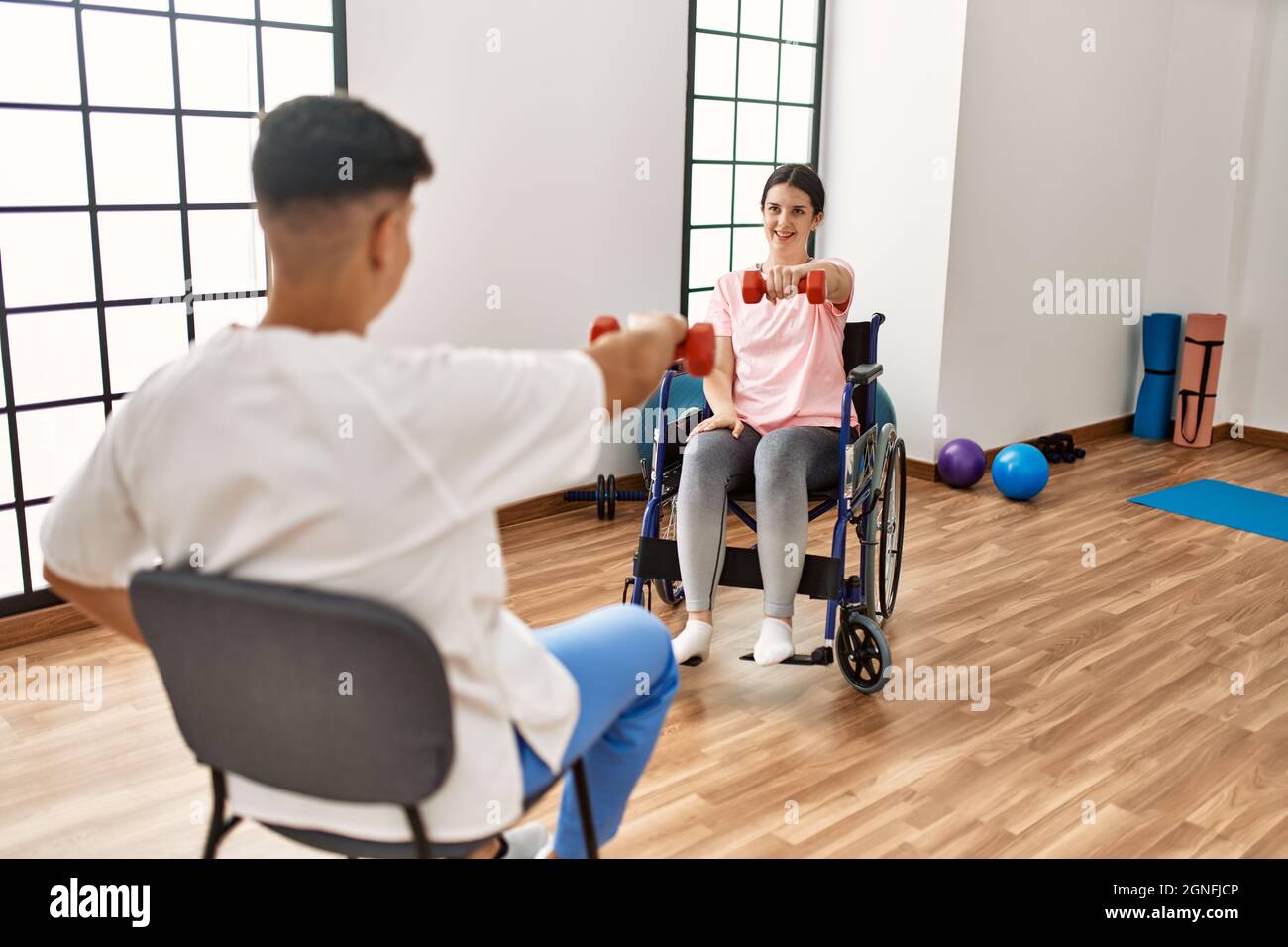 Young disabled woman sitting on wheelchair making mobility exercise ...