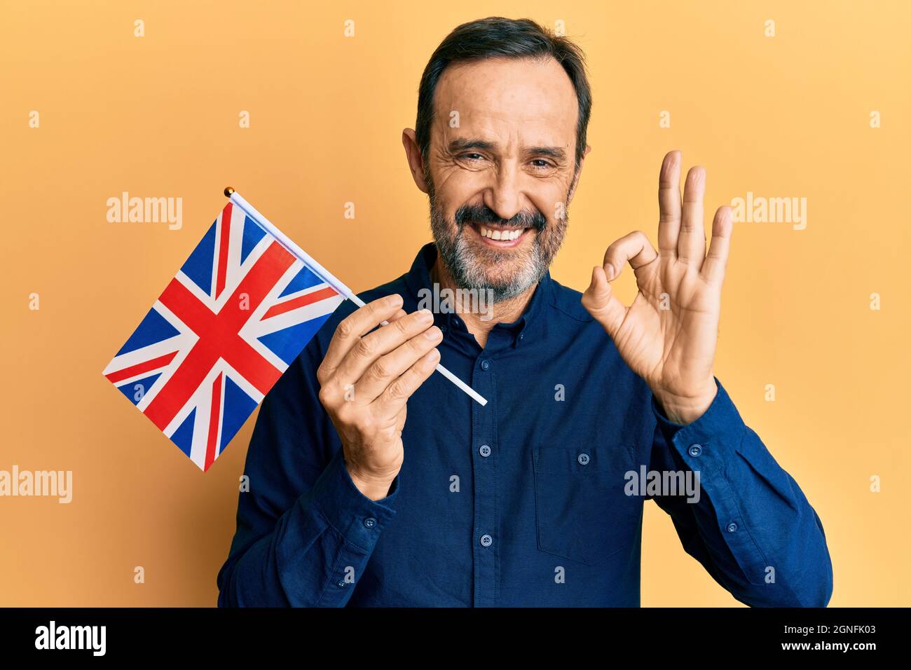Middle age hispanic man holding united kingdom flag doing ok sign with ...
