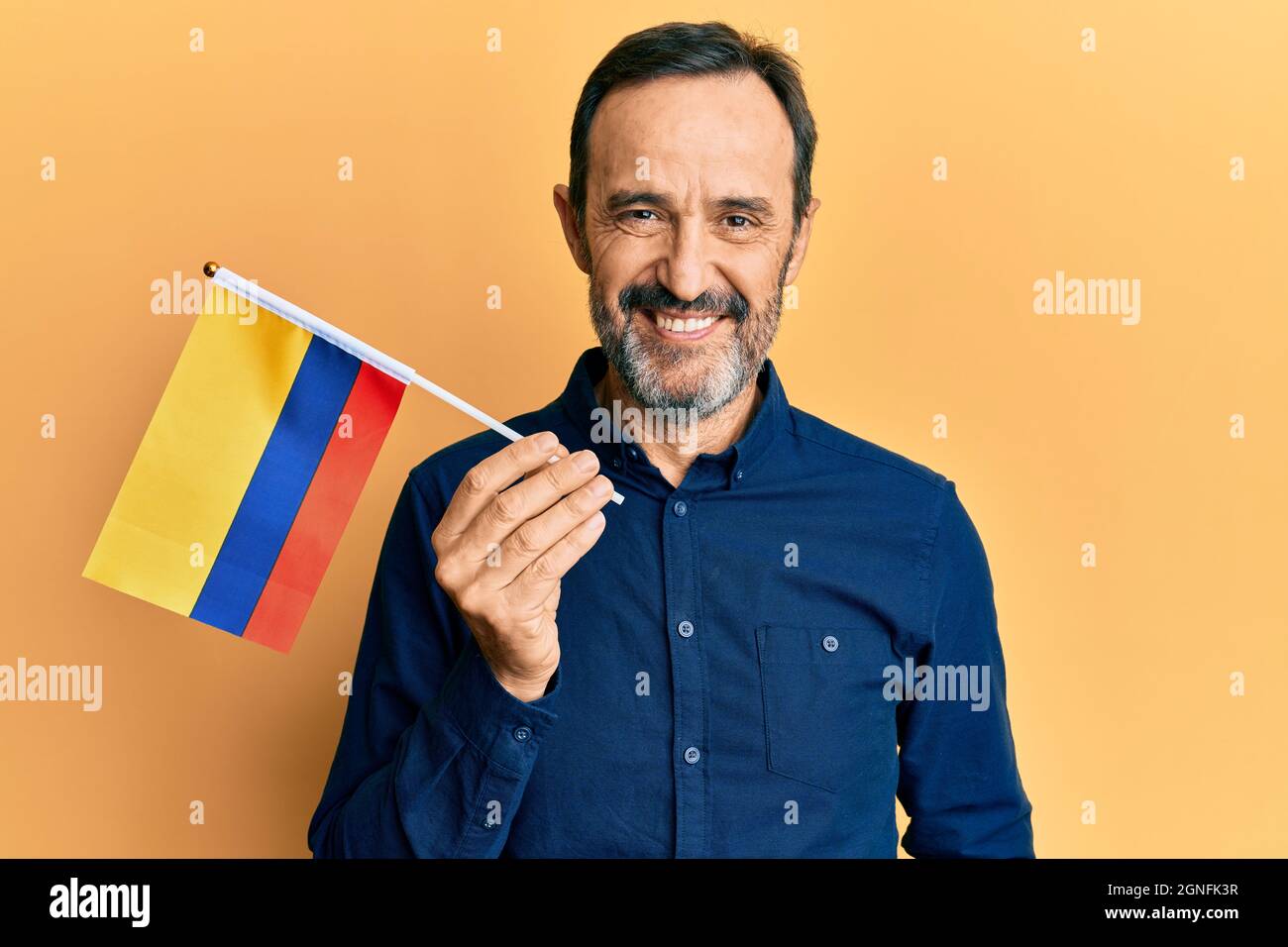 Middle age hispanic man holding colombia flag looking positive and ...