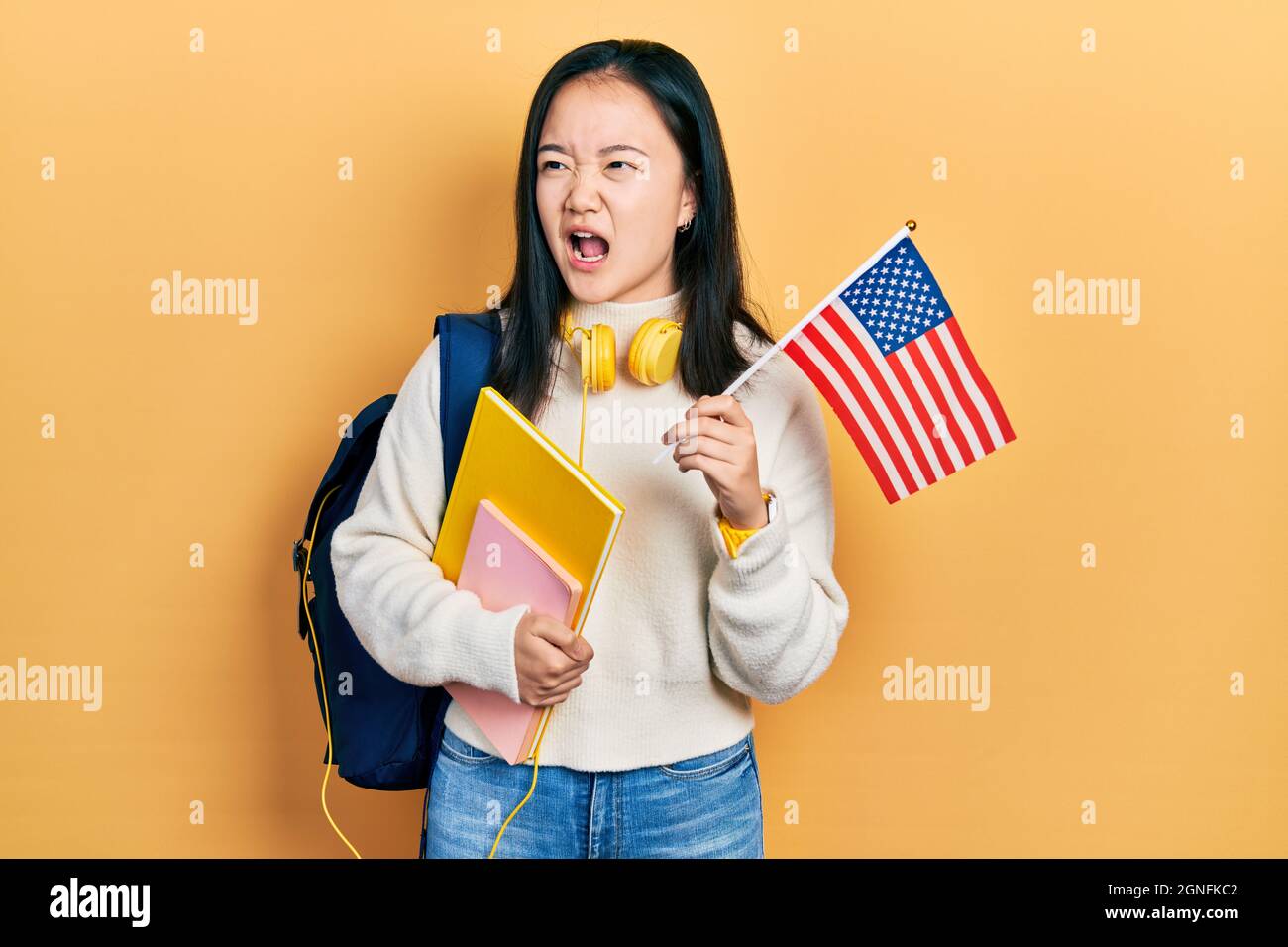 Young chinese girl exchange student holding america flag angry and mad ...