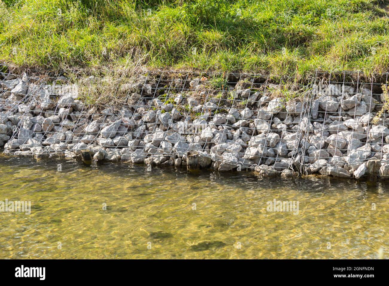 Fortification on the river bank. A stream bank with a stone gabion wall ...