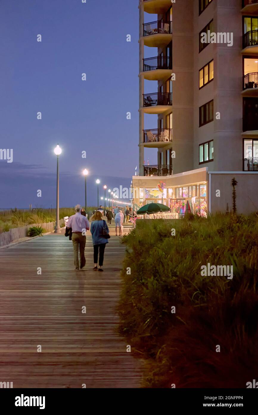 Couple strolls along the Rehoboth Beach, Delaware boardwalk at night ...