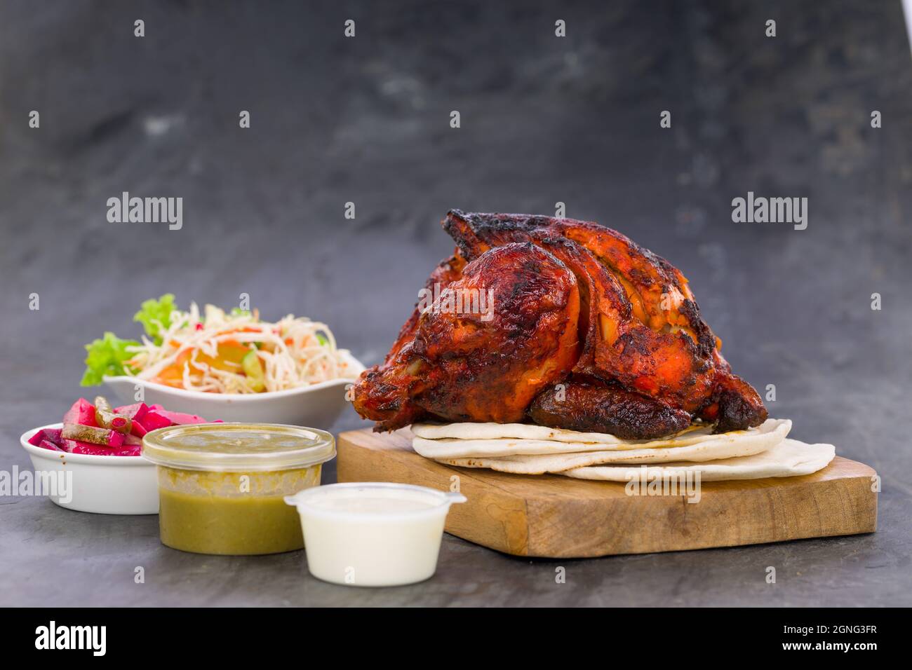 Shawai chicken arranged on a wooden base with kuboos and side dishes on ...